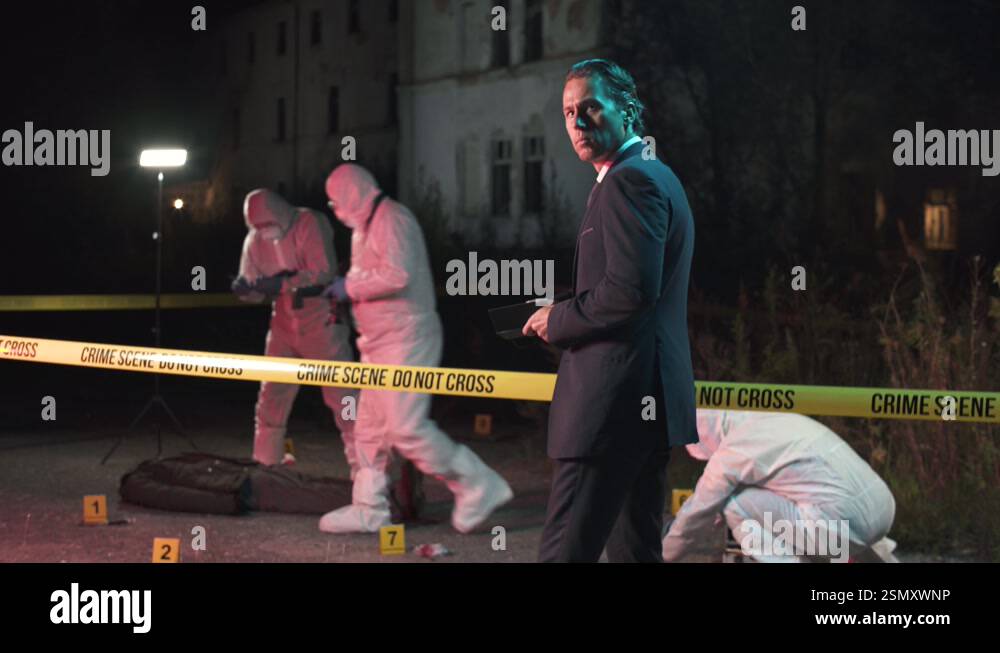 Detective inspecting area and taking notes in notebook at crime scene ...