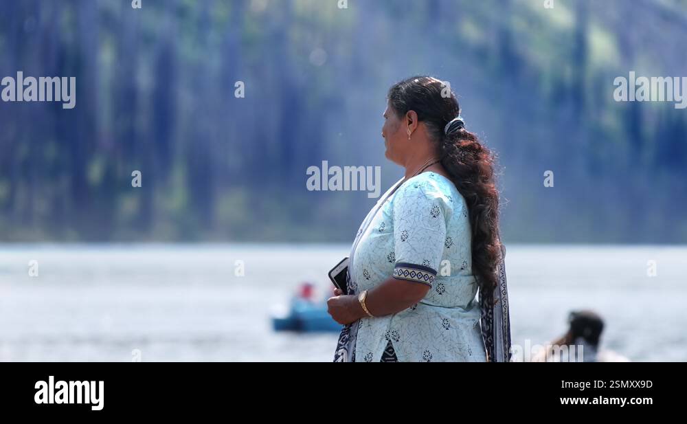 A woman in traditional attire smiles peacefully, standing by the ...