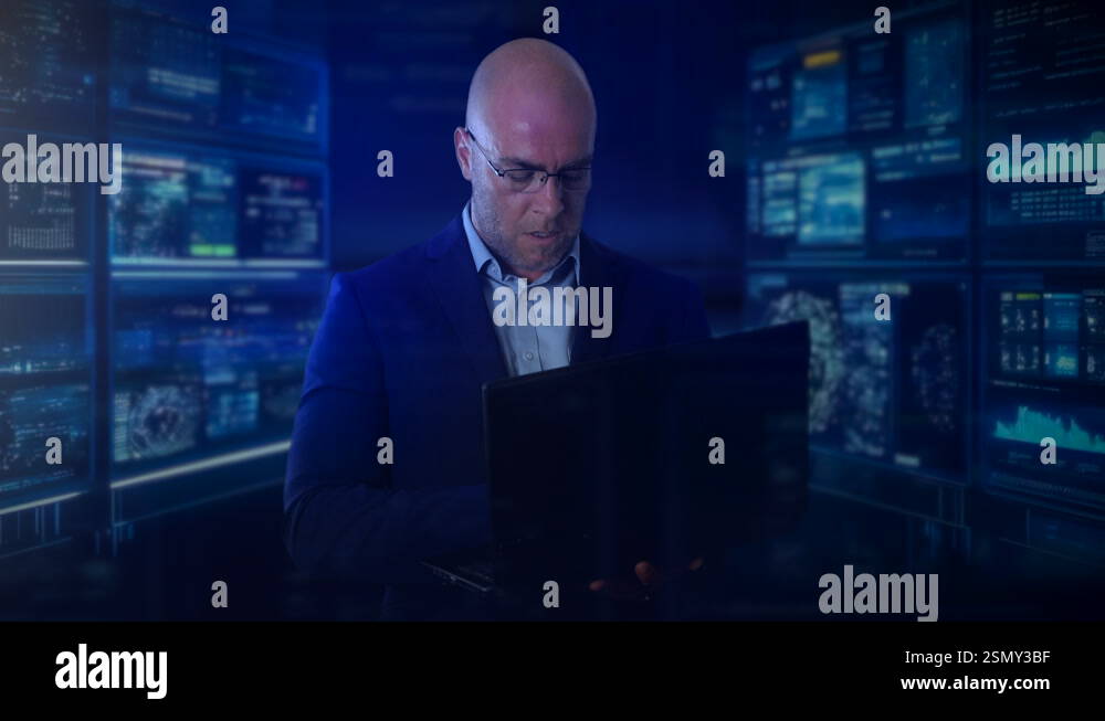 A computer programmer in a suit is using a laptop, standing in front of ...
