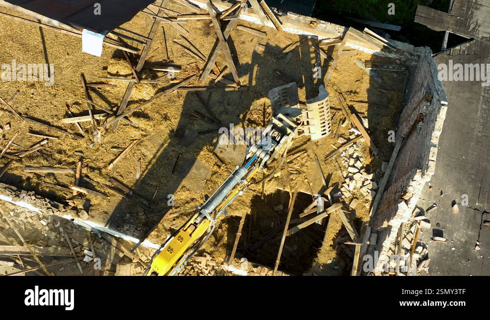 Overhead view showing an excavator claw removing wooden debris from a ...