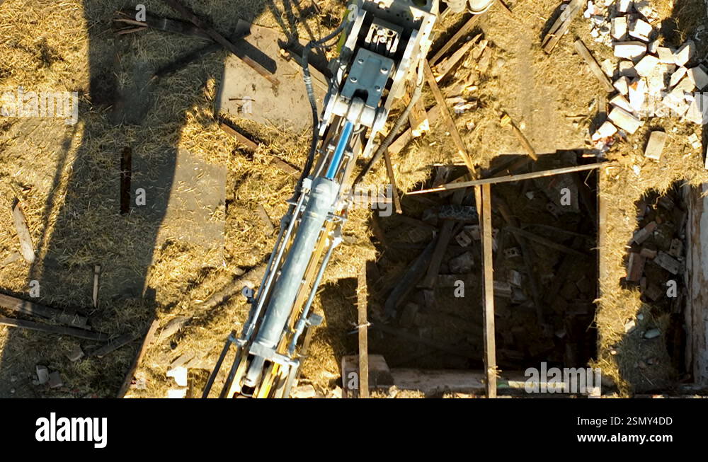 Top-down view showing an excavator claw breaking through a building ...