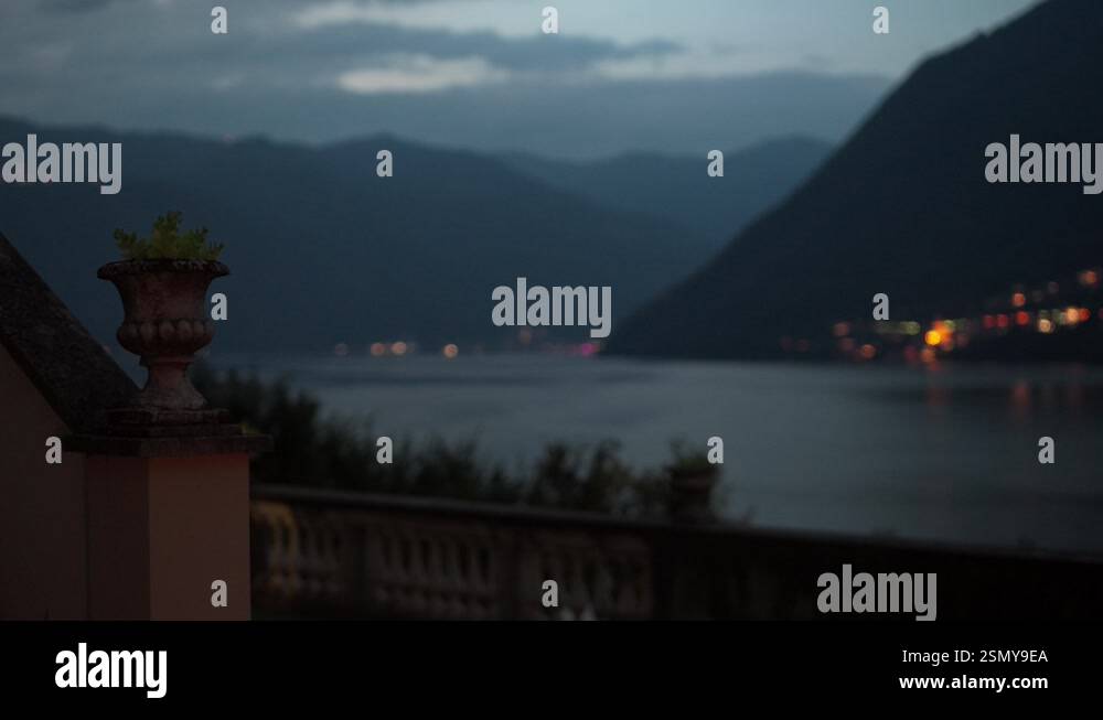A balcony vista of Lake Como at dusk. The camera focus racks from the ...