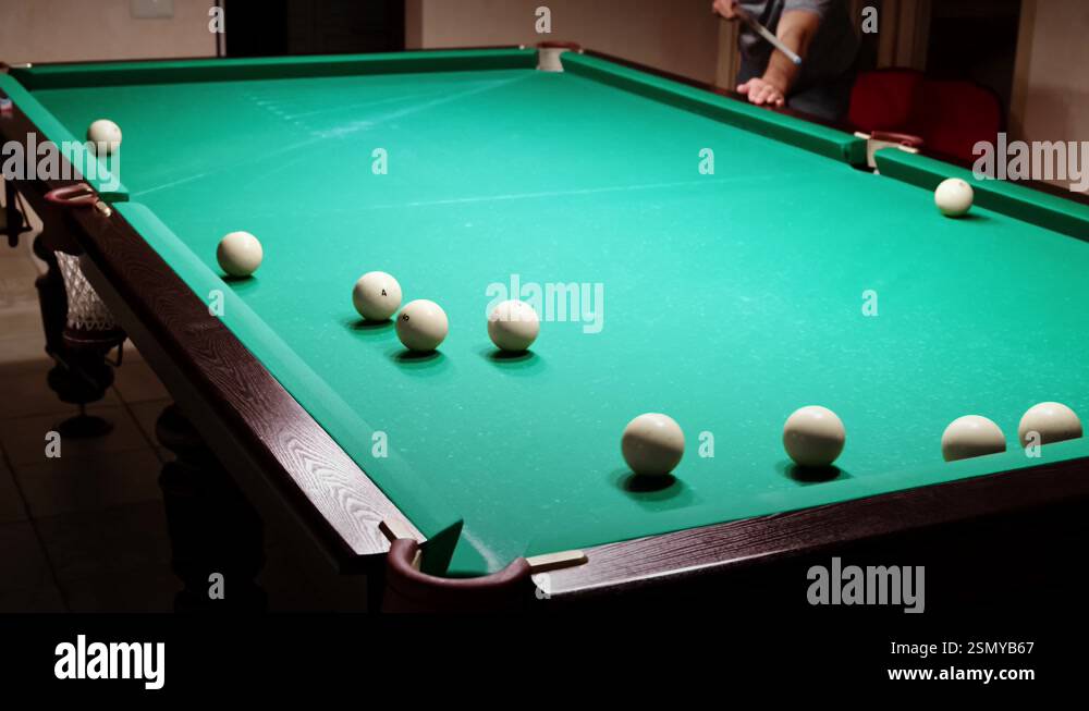 Playing Russian billiards on a green table. A beginner player hits a ...