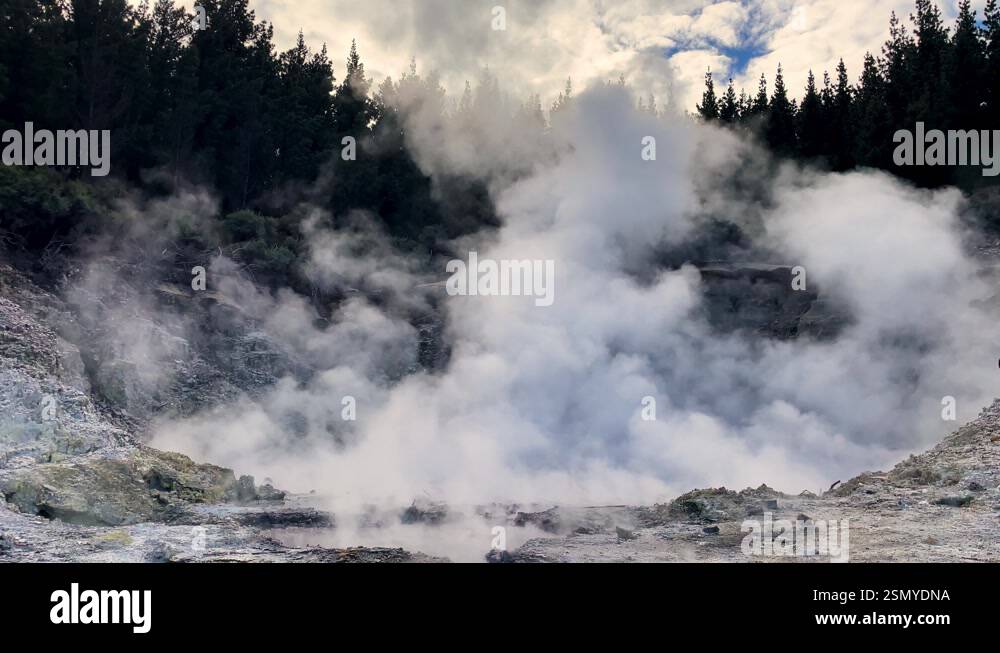 A plume of steam rises from a boiling hot spring in a rocky volcanic ...