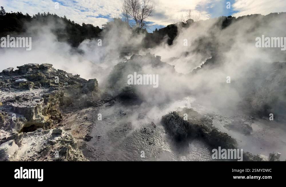 Steam rises from a bubbling hot pool in a rocky volcanic landscape in ...