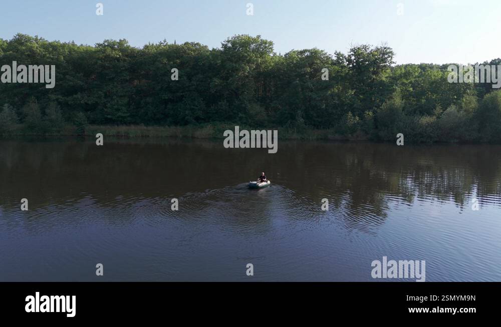 A fisherman is fishing for carp on his boat on a Polish lake on a ...