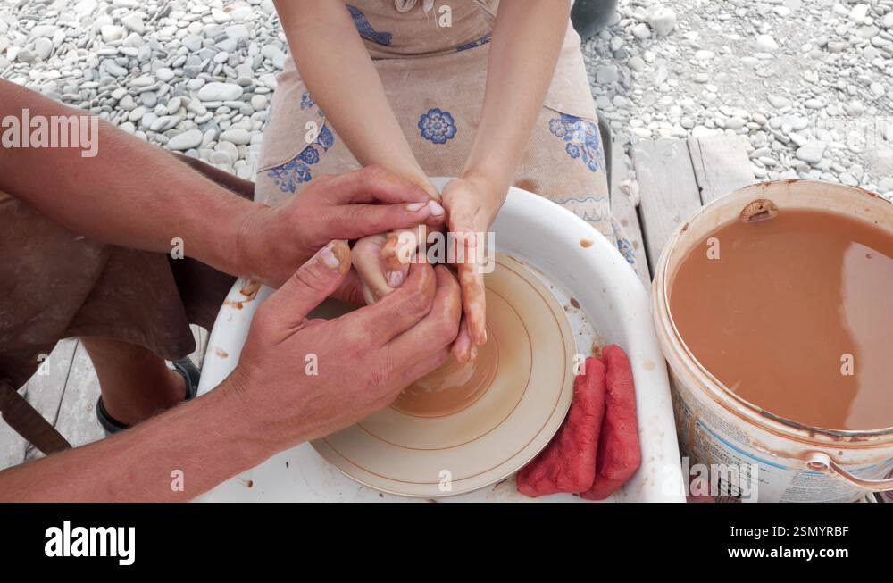 Man training girl sculptor or artist on spinning table for pot mold ...