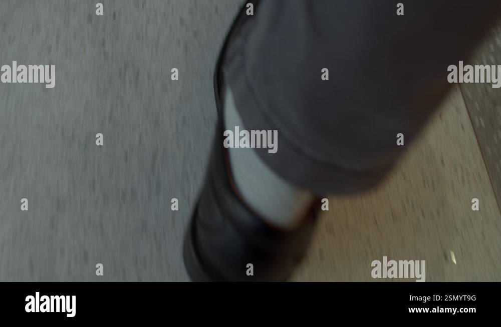 Slow motion of a man's foot taking a step in an airport terminal tiled ...
