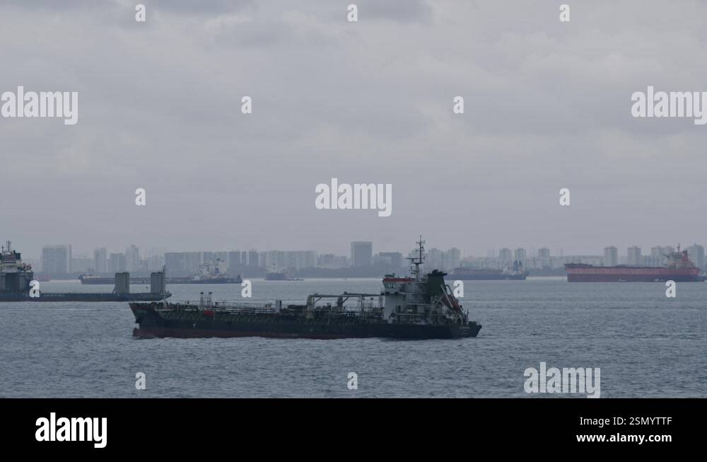Cargo ships moving across the waters with a city skyline in the ...