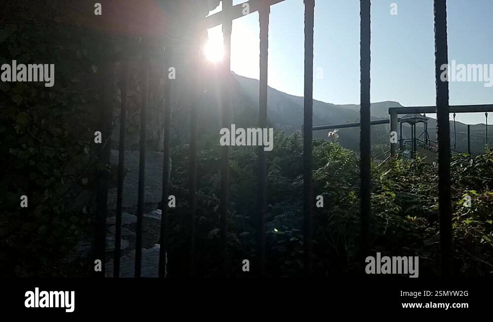 Looking through medieval iron gate bars at sun rising above mountain ...
