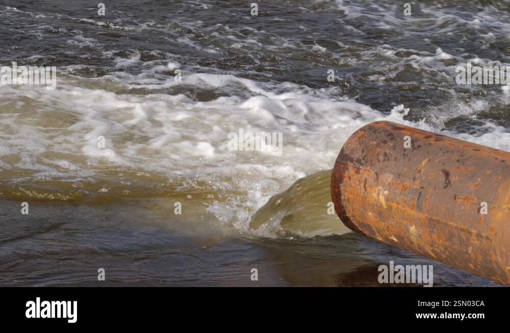 dirty waste water flows from a pipe into a river polluting and ...
