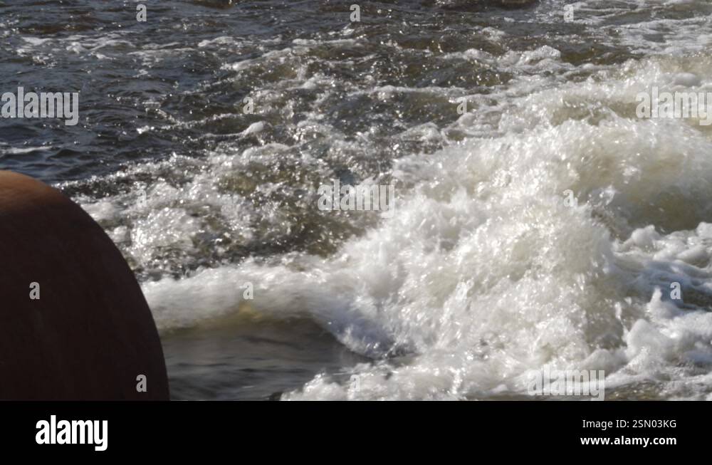 dirty waste water flows from a pipe into a river polluting and ...
