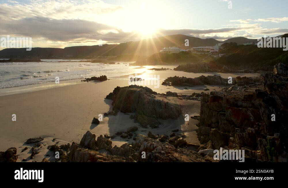Tranquil beach scene in Hermanus as sunburst of sun bathes pristine ...
