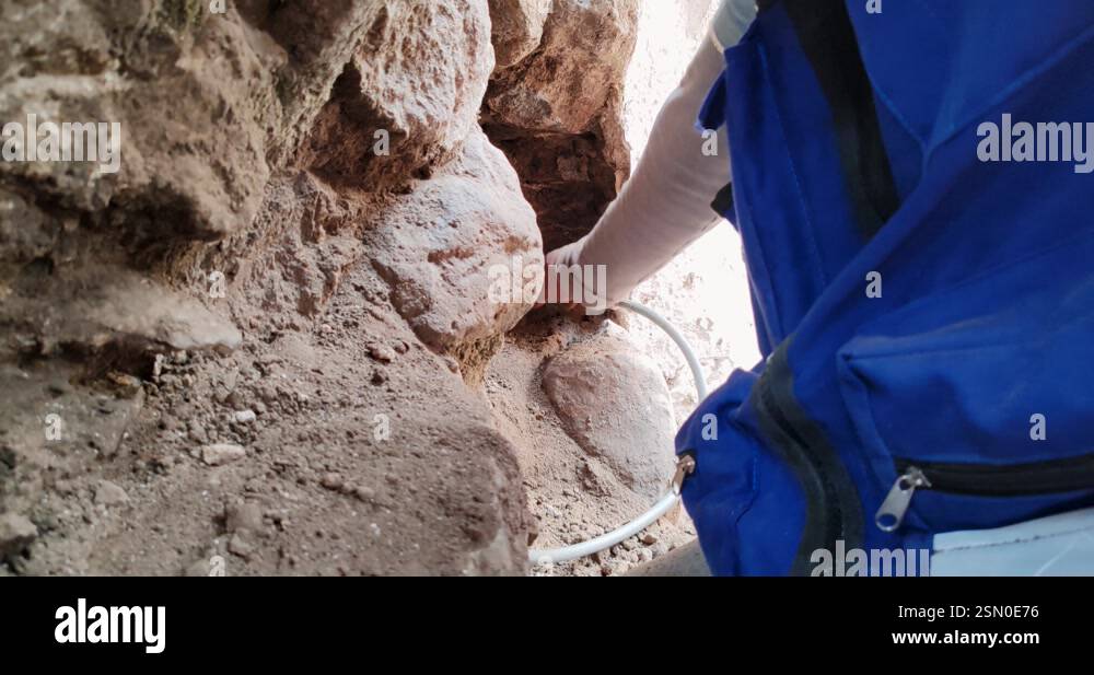 Worker applying compressed air to remove volatile material from a stone ...
