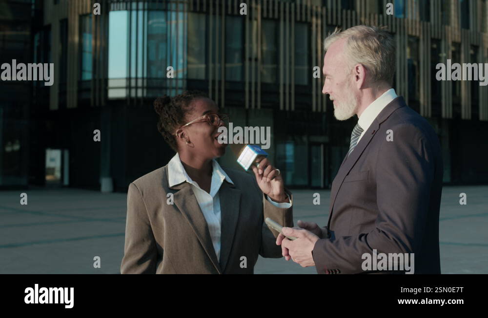 Female Reporter Conducting Interview with Businessman Outside Modern ...