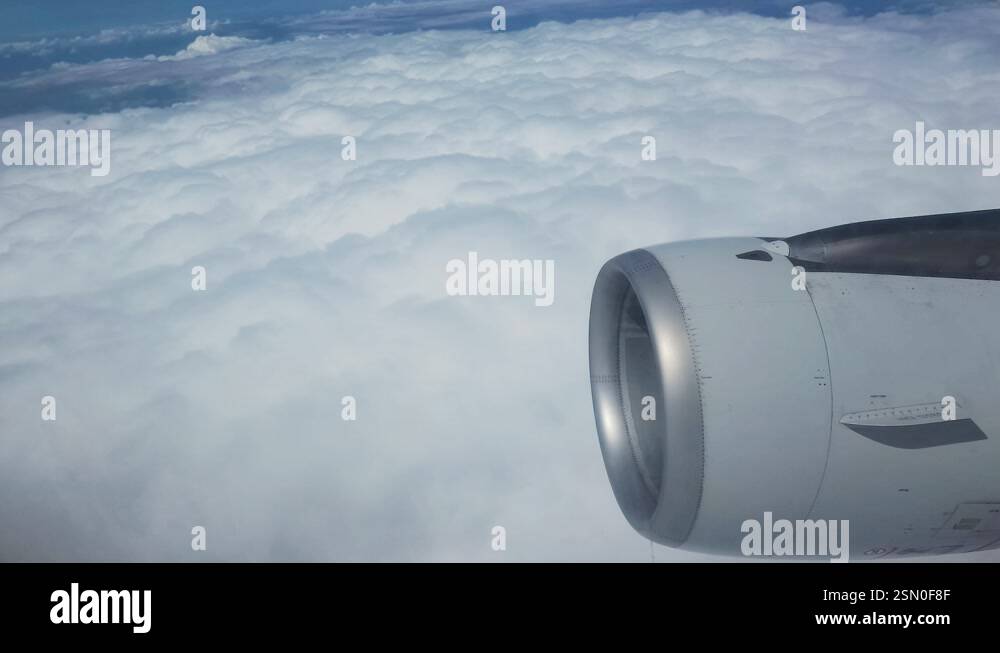 Airplane wing and engine soaring above a sea of fluffy white clouds ...