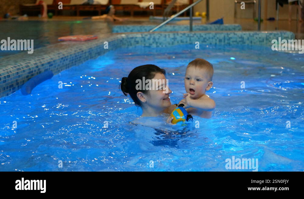Little baby boy and his mother learning to swim in an indoor swimming ...
