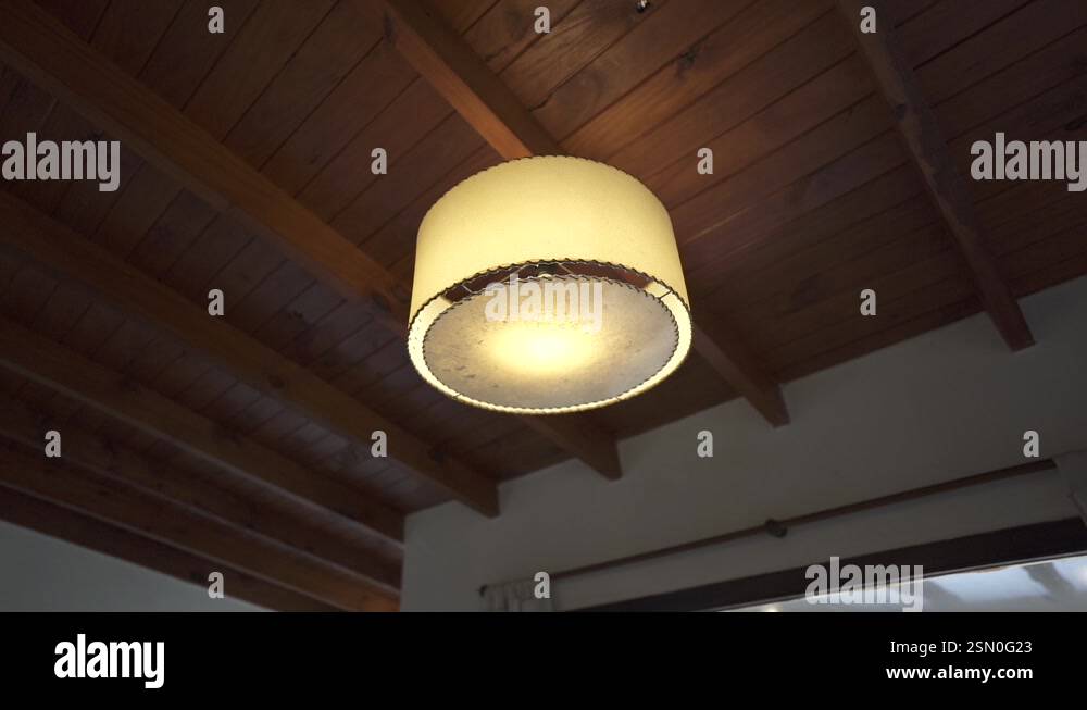 Warm light fixture hangs from a wooden ceiling in a modern home ...