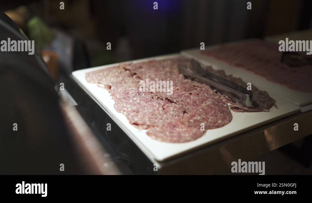 Salami pieces on buffet food serving board in hotel restaurant. Gourmet ...