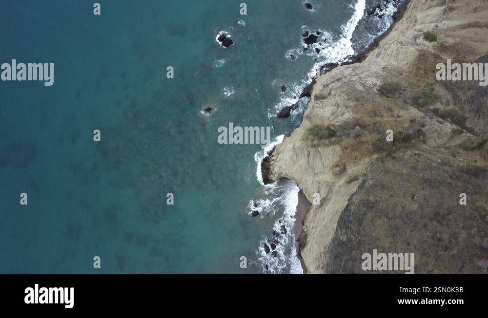 Rocky steep limestone cliff edge, light waves Pacific Ecuador coastline ...