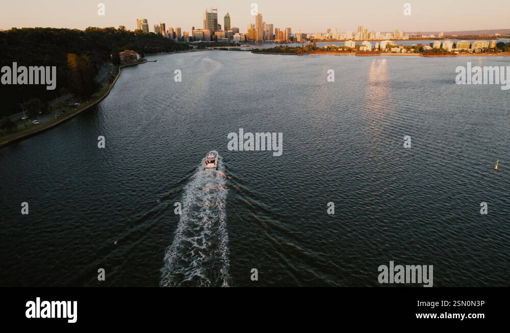 Sunset view of a boat cruising on the river with a skyline backdrop ...