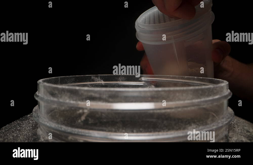 A hand places a Mesh Strainer Lid onto a Shaker Cup filled with Protein ...