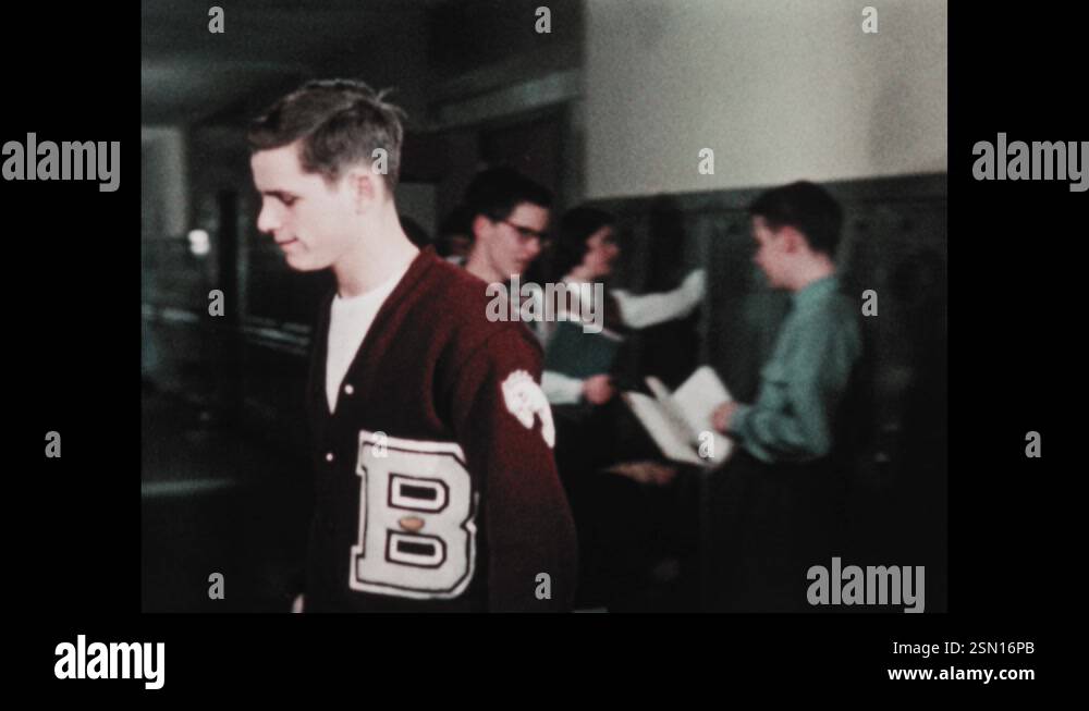 1950s: Awkward student walks away from group of boys talking at hallway ...