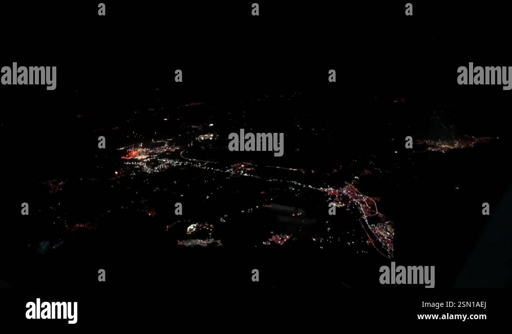 City lights glowing from an airplane window during night flight over an ...