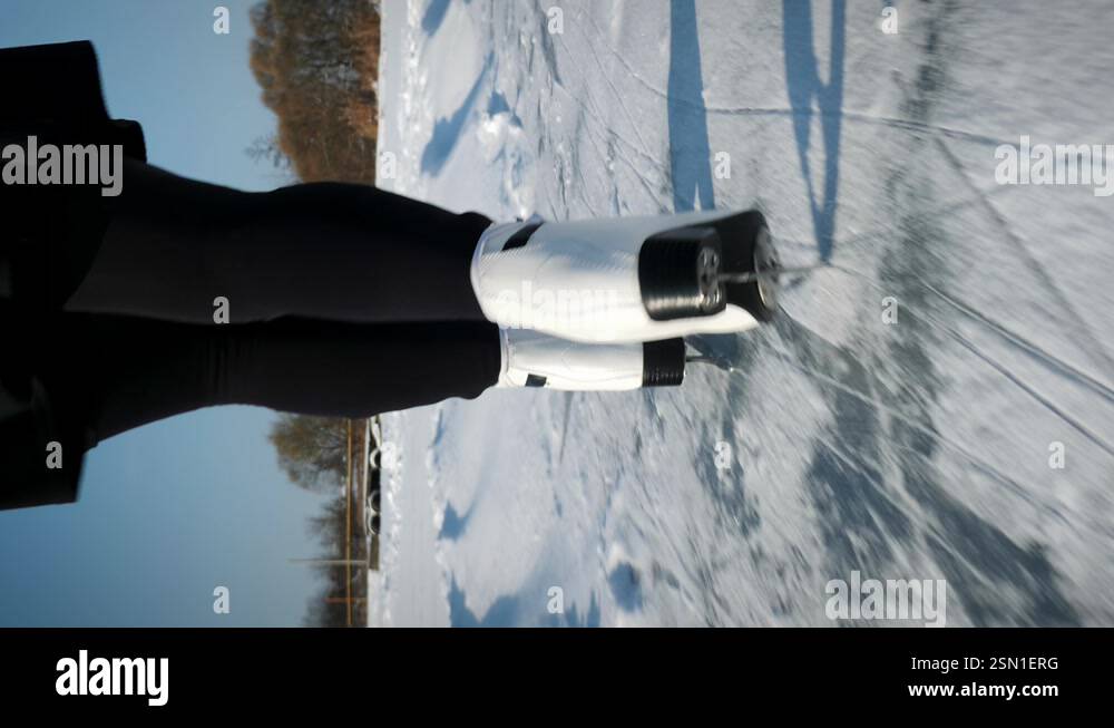Woman feet in white skates are ice skating on ice lake, close up ...