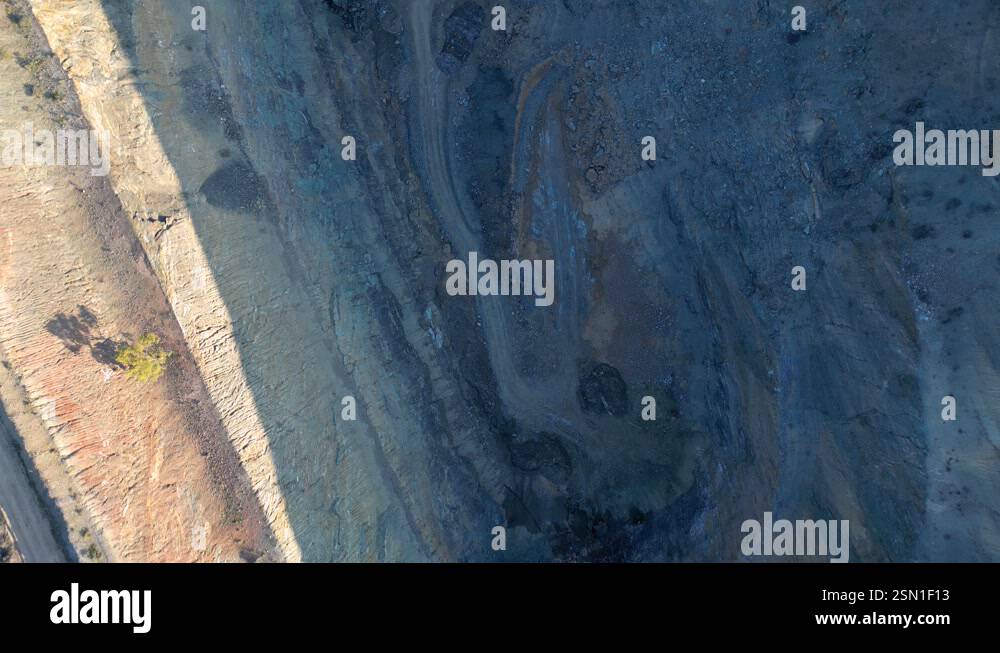 Top down aerial of large open-pit gold mine with winding roads deep ...