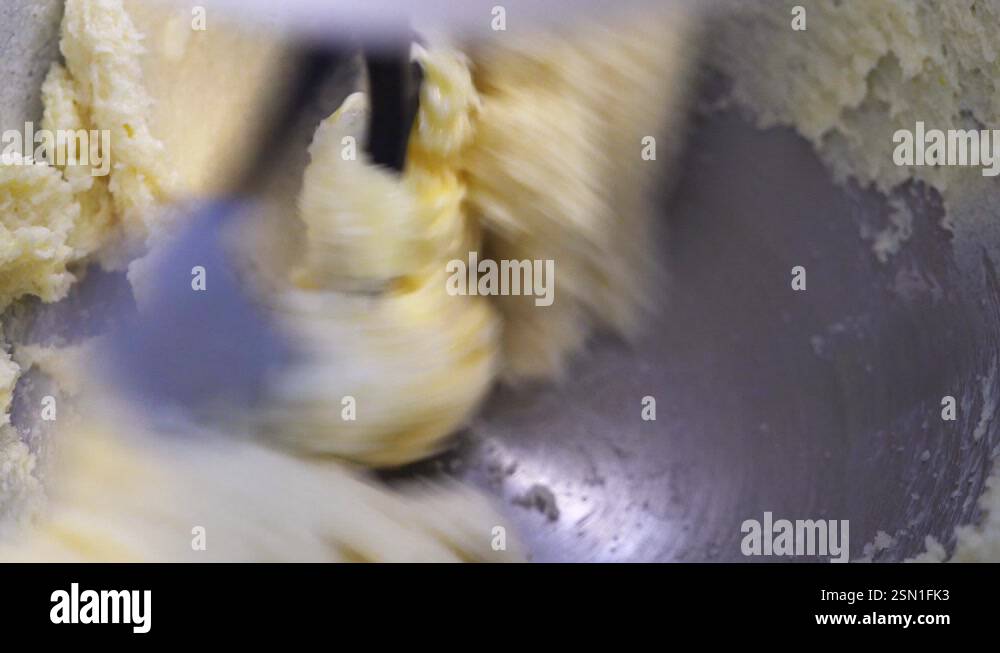 Slow-motion closeup of a beater creaming sugar and butter in a ...