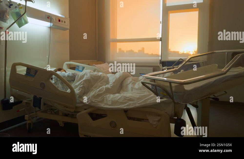 Woman breastfeeds her newborn lying on the bed after giving birth by ...