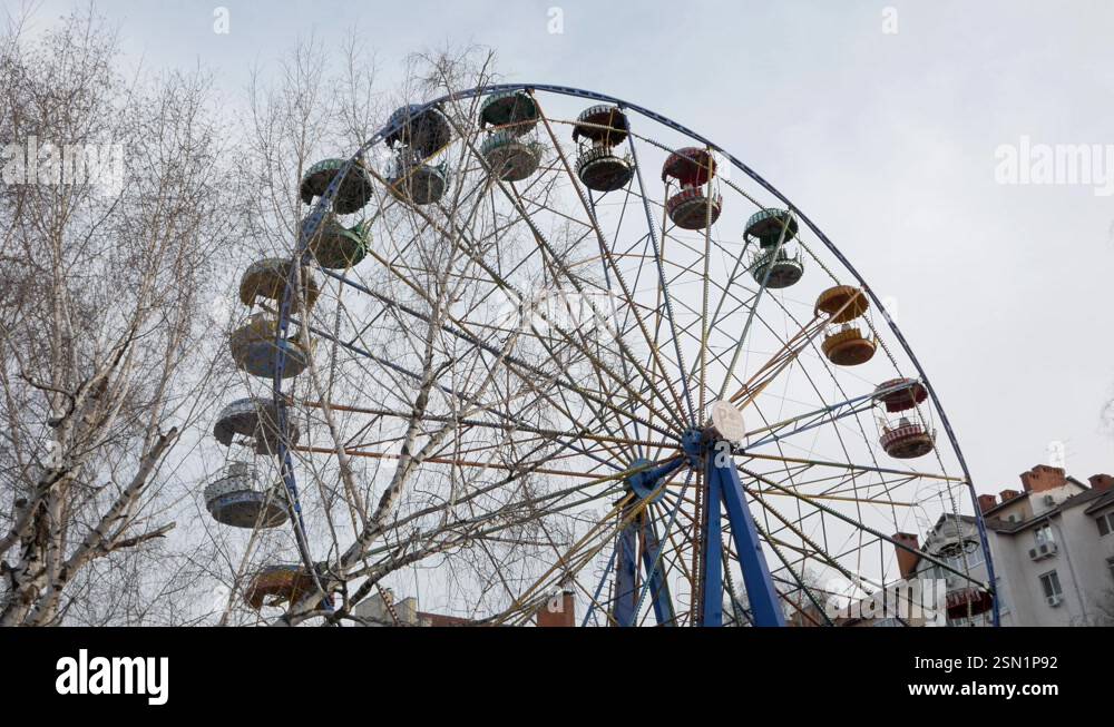 Ferris wheel spinning against background of sky and trees. Spring. The ...