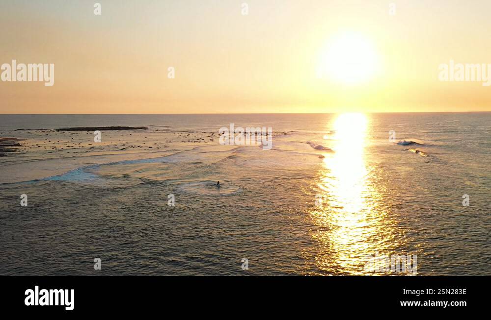 Ocean sunrise aerial pullback view of jet ski and sun reflection on ...