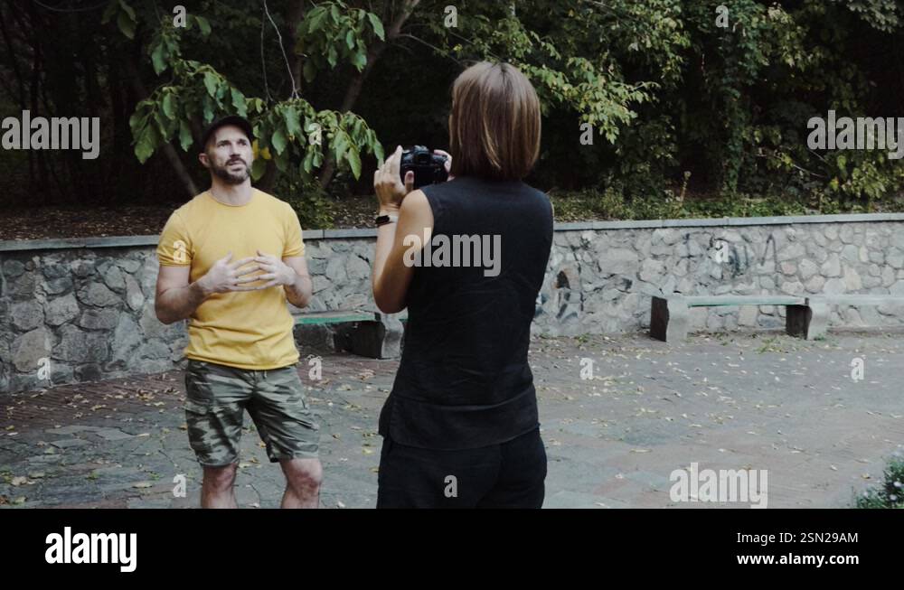 A man and a woman chat and learn how to take photos using a DSLR camera ...