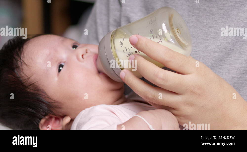 Mother feeding her newborn baby some milk as she cradles her child in her Stock Video Footage ...
