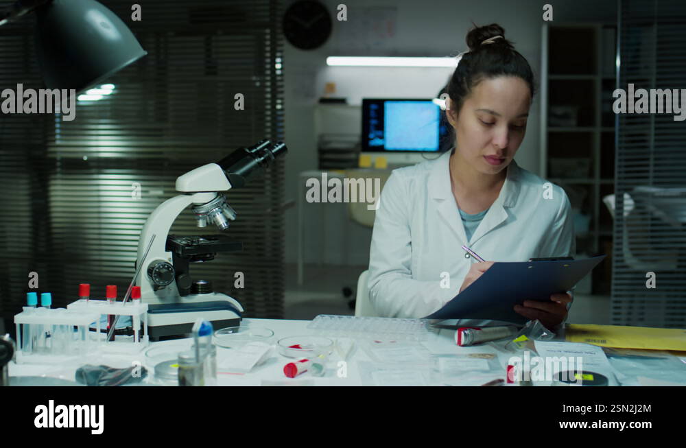 Female Forensic Scientist Analysing Bullet and Taking Notes in Crime ...