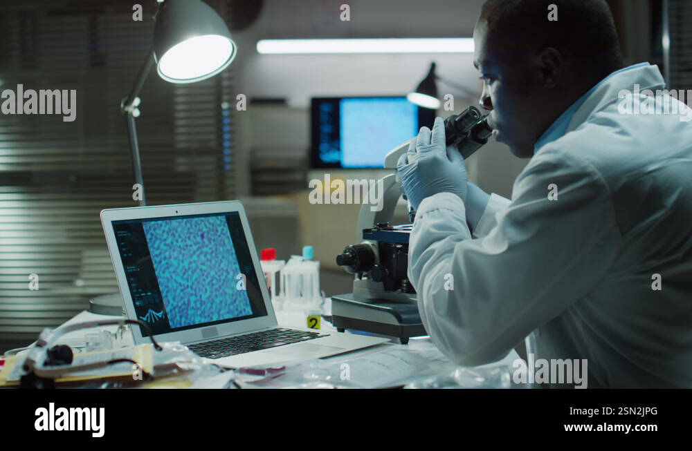 Forensic Scientist Examining Evidence under Microscope Connected to ...