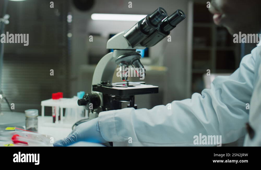 Serologist Examining Blood under Microscope Connected to Digital Tablet ...