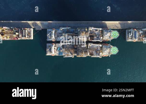 Several oil rigs are seen anchored at the harbor under clear skies ...
