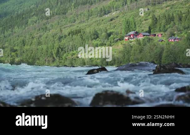 Norway mountains with flowing river over rock with village on hill in ...