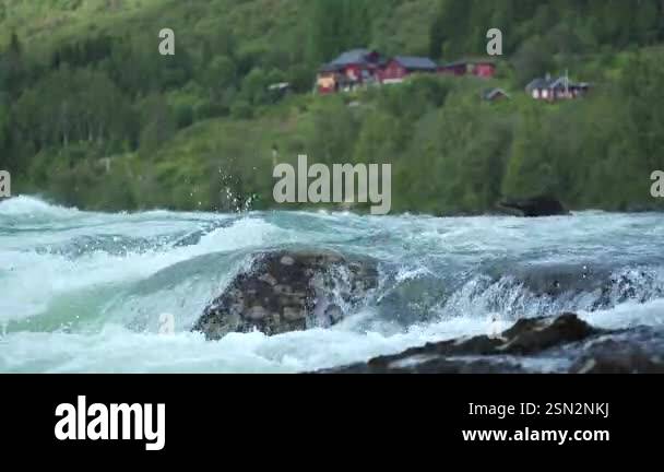 Norway mountains with flowing river over rock with village in ...