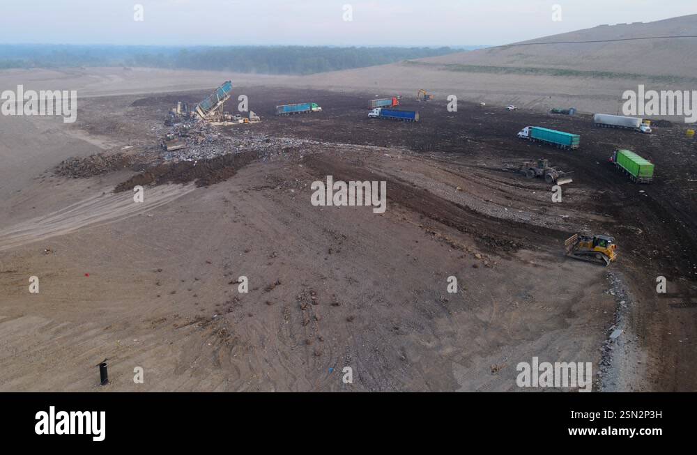 Landfill site with trucks unloading waste in a large open area ...