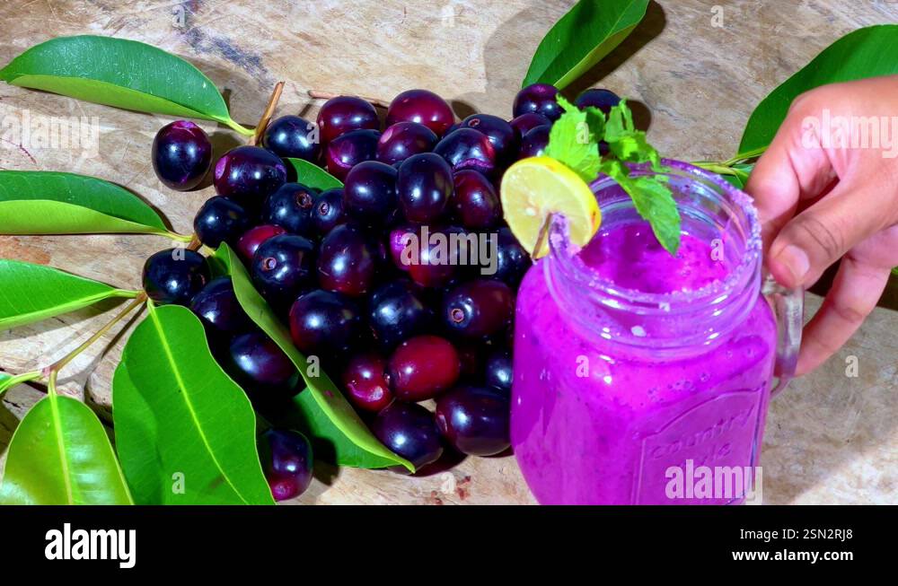 placing a jamun juice jar beside some jamun fruits and topped with ...