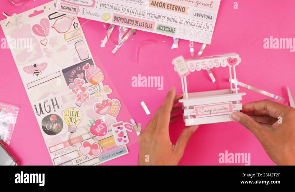 Putting stickers on miniature kissing booth made from popsicle sticks ...