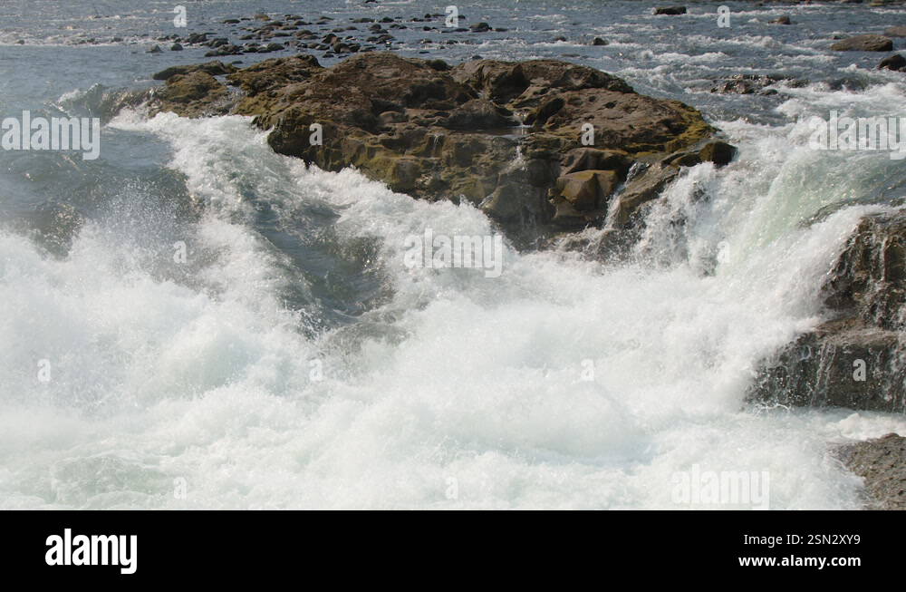 Slow motion whitewater pouring over high flow waterfall, rock island ...