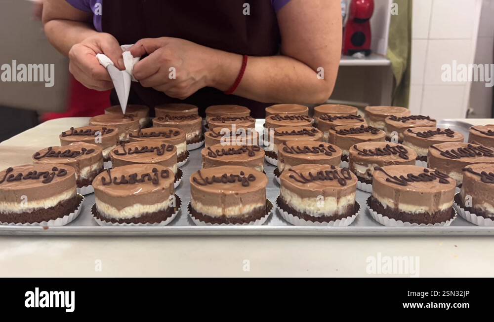 Time lapse of a female pastry chef writing names in her chocolate cakes ...
