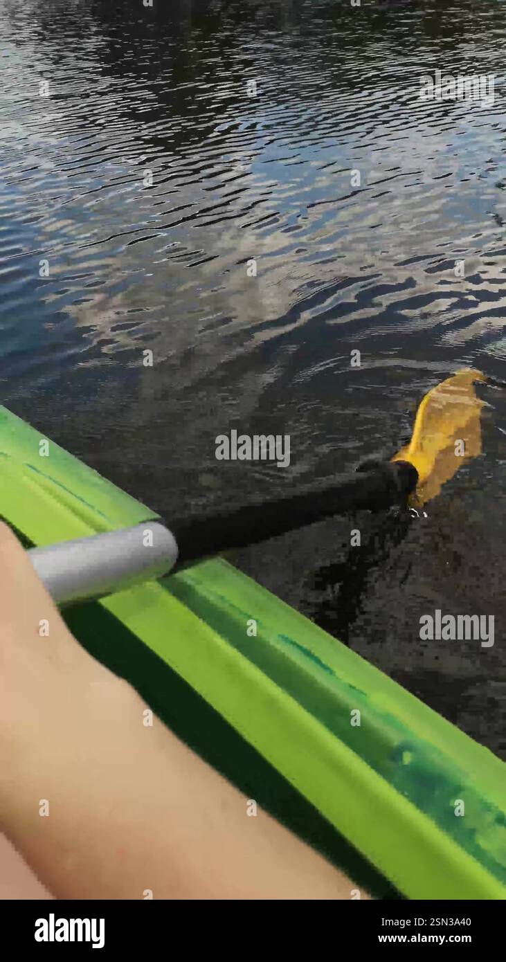 Vertical 4K video showing first-person view of a woman's hand paddling ...