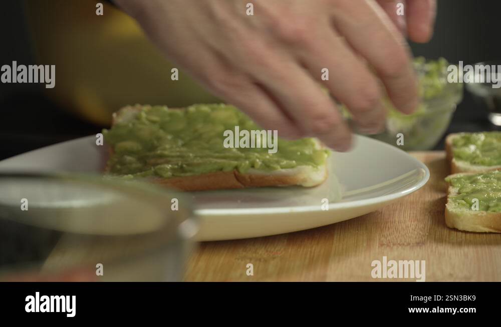 Hands of middle man european putting toasts with guacamole on a plate ...