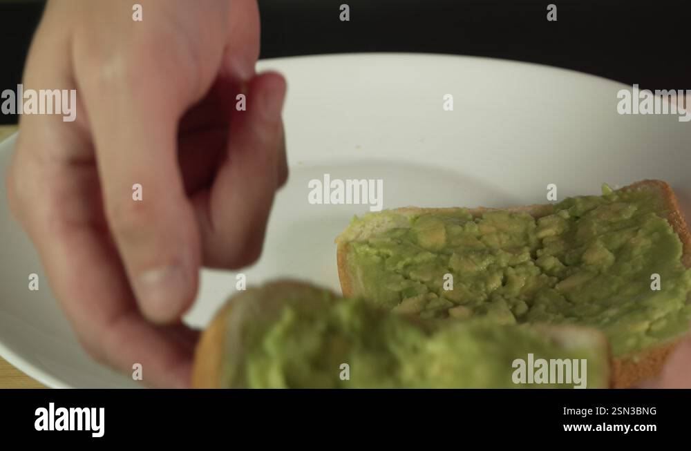 Hands of middle man european putting toasts with guacamole on a plate ...
